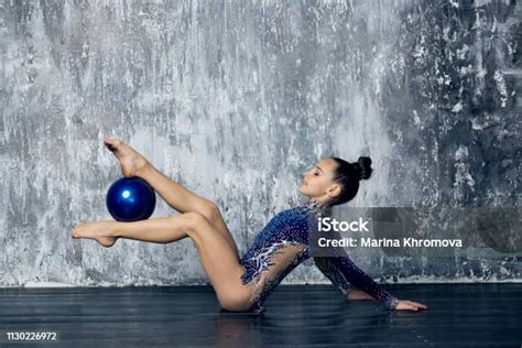 반짝임을 가진 파란 벌에 있는 소녀 선수 리듬 체조는 바닥에 스포츠 공을 가진 운동을 만듭니다 가냘픈에 대한 스톡 사진 및 기타 이미지 Istock