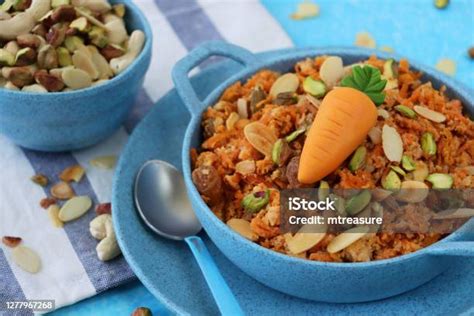 블루 볼 접시 숟가락 가자르 카 할와 달콤한 인도 디저트 푸딩 달게 간 당근과 아몬드 차 수건과 혼합 아몬드 캐슈와 피스타치오 견과류의 그릇 옆에 전경에 초점을 맞추고 전