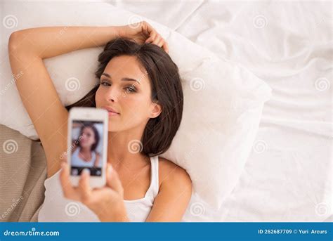 Snapshot A Beautiful Young Woman Taking A Selfie While Relaxing In Bed