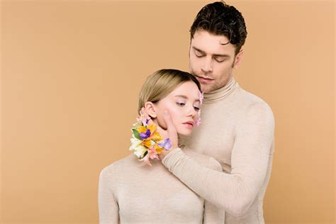 베이지색에 고립 된 예쁜 여자 친구의 손을 만지고 얼굴에 Alstroemeria 꽃과 부드러운 남자 2명에 대한 스톡 사진 및