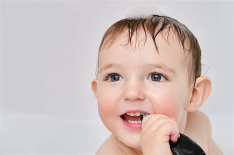 행복한 유아 아기는 거품 욕조에 앉아있는 치아를 닦습니다 아이는 씻고 칫솔로 이빨을 닦는 법을 배웁니다 일년 세 달 된 아이 12 17 개월에 대한 스톡 사진 및 기타