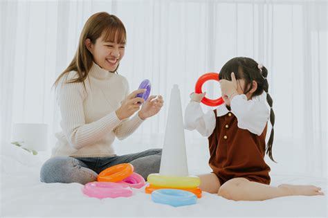 엄마와 어린 4세 딸이 거실에서 함께 다채로운 반지 장난감을 가지고 있다 20 24세에 대한 스톡 사진 및 기타 이미지 20
