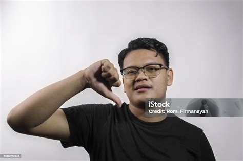 白い背景に親指を下に向けるジェスチャーを示す若いハンサムなスマートなアジア人男性 1人のストックフォトや画像を多数ご用意 1人 20
