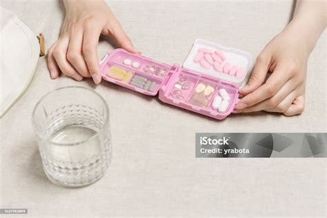 분홍색 알약 상자를 손에 들고 테이블에서 약을 마시는 젊은 여성 여성 건강 개념 치료 및 건강을 위한 대체 의학으로서의 약물