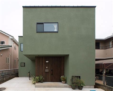 A Green Building With A Wooden Door And Window On The Side Of Its Face