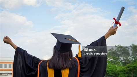 졸업식에서 졸업 후 검은 색 아카데믹 가운과 모자를 쓰고 졸업식에서 즐거운 순간을 가진 학위 증서를 소지하고 있는 여성 대학
