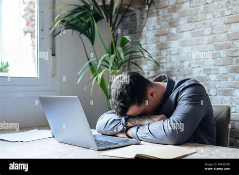 Exhausted Young Caucasian Male Employee Sleep Desk At Office Overwork Preparing Report Tired