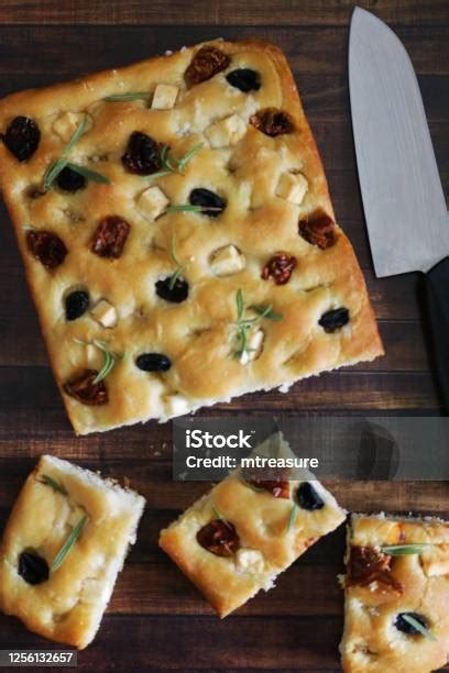 부엌 칼 녹색 올리브 햇볕에 말린 토마토와 로즈마리 잎 장식 높은 전망과 페타 치즈나무 도마에 슬라이스 수제 이탈리아 어 빵