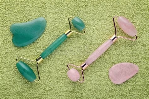 Real Jade Facial Roller And Rose Quartz On Green Background With
