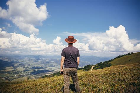 세련 된 여행자 남자가 전화를 들고 모자 맑은 산과 하늘 위에 걷고 있다 여행과 방 랑 벽 개념입니다 텍스트를 위한 공간입니다