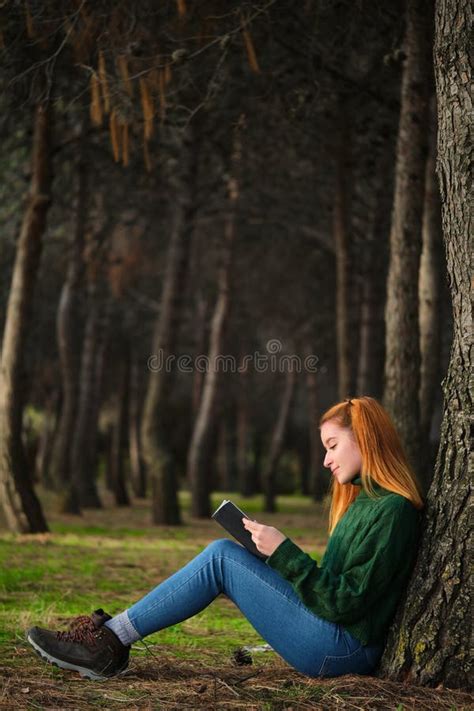 Joven Pelirroja Leyendo Un Libro Sentado Bajo Un árbol En Un Bosque