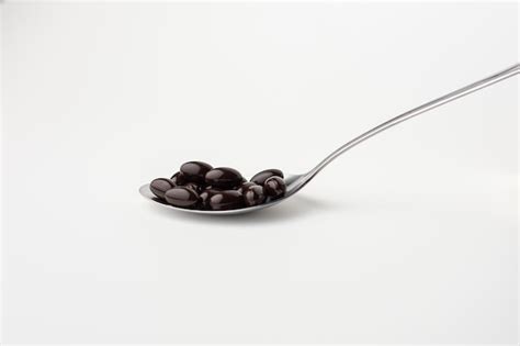 Cápsulas De Gelatina Blanda Negra En Una Cuchara De Acero Inoxidable