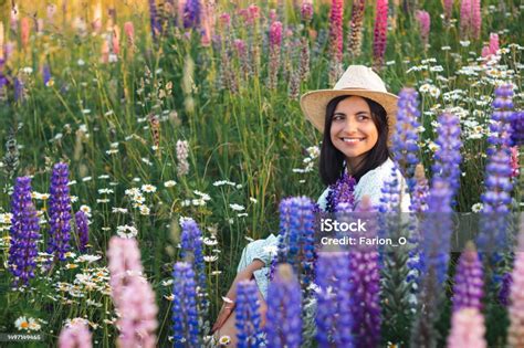 드레스와 밀짚모자를 쓴 젊은 매력적인 여성의 초상화는 해질녘 여름 초원에 만개한 루팡 꽃의 꽃다발을 들고 있다 걷기에 대한 스톡 사진 및 기타 이미지 Istock
