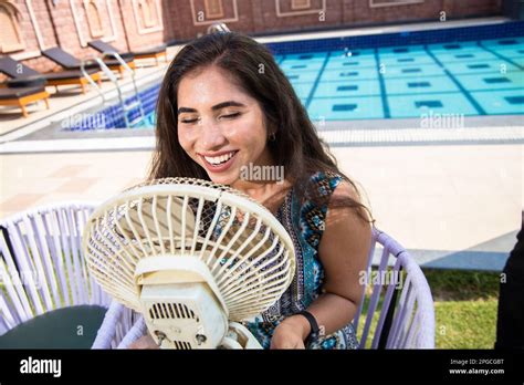 Young Indian Woman Enjoying Air Flow From Electric Fan And Cooling Her