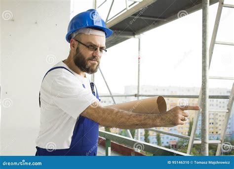 Bad Construction Worker In Working Overall And In Helmet Stands At A