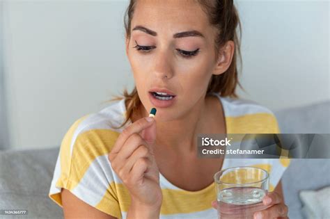 여자는 물 한 잔으로 약을 먹는다 비타민의 일상 규범 효과적인 약물 신체 및 정신 건강 개념을위한 현대 약국 감기와 독감에 대한