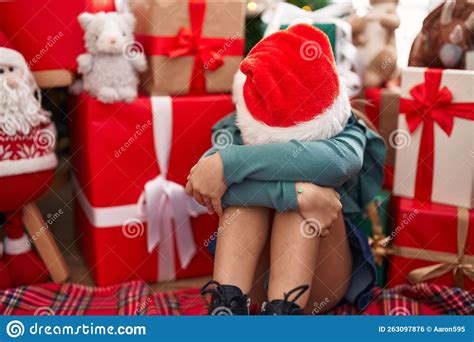 Adorable Hispanic Girl Sitting On Floor By Christmas Tree Crying At