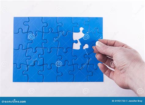 Woman S Hand Placing Missing Piece In Jigsaw Puzzle Signifying Stock