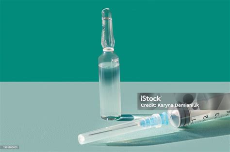 청록색 유리 앰플 플라스크에 액체와 주사기가 있는 청록색 배경에 단단한 그림자가 있습니다 가능한 코로나 바이러스 백신의 복용량