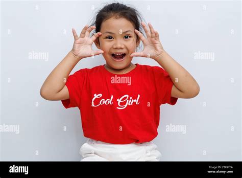 Little Asian Girl Raises Both Hands Parallel To Her Head Making A