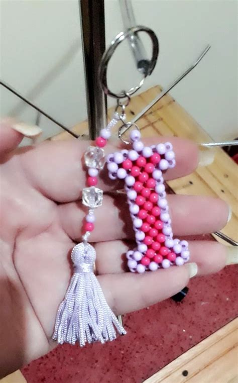 A Hand Holding A Beaded Cross And Tassel