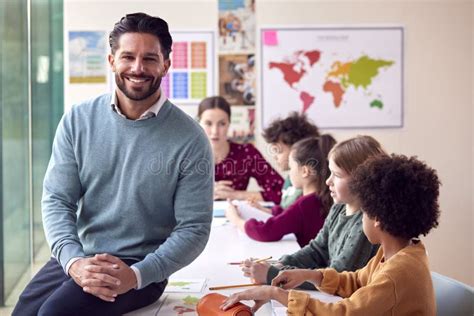 Portrait Of Smiling Male Elementary School Teacher Working At Desk In
