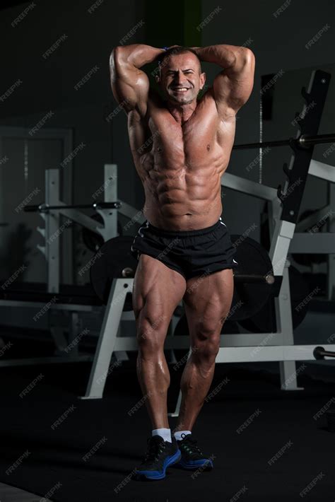 Belluomo Maturo In Piedi Forte In Palestra E Flettendo I Muscoli