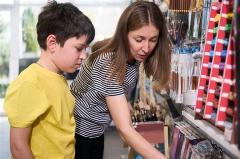 Teenage Schoolboy Choosing School Supplies Asking For Advice From The