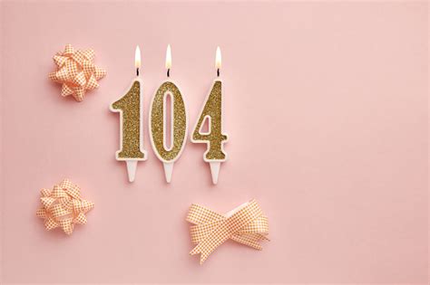 축제 장식이 있는 파스텔 핑크 배경에 숫자 104가 있는 양초 생일 축하 촛불 생일 기념일 중요한 날짜 휴일을 축하하는