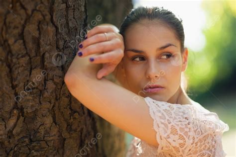 Thoughtful Young Woman Lean Against Tree Photo Background And Picture