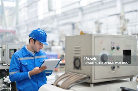 반신 사진 업 미국 남성 엔지니어 그는 대형 플라스틱 및 금속 공장에서 유니폼과 헬멧을 착용하고 작업 기계의 제어판 근처에서