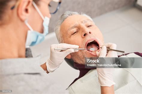 의사가 일부 기기를 사용하여 환자의 치아를 검사합니다 2명에 대한 스톡 사진 및 기타 이미지 2명 40 44세 65 69
