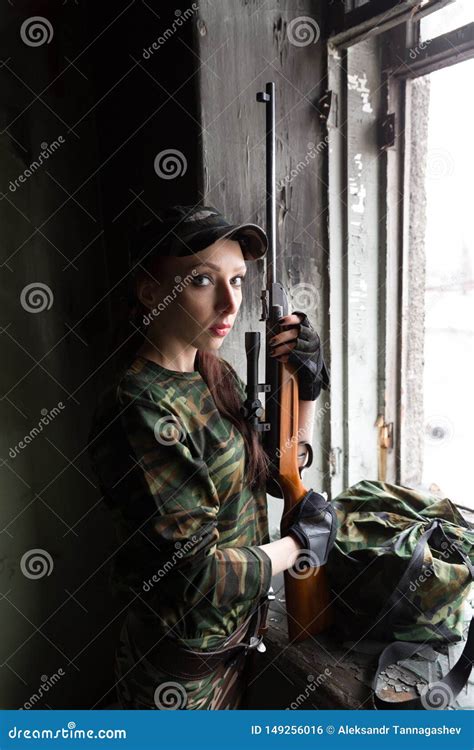A Thin Red Haired Girl Stands At The Broken Window With A Rifle The