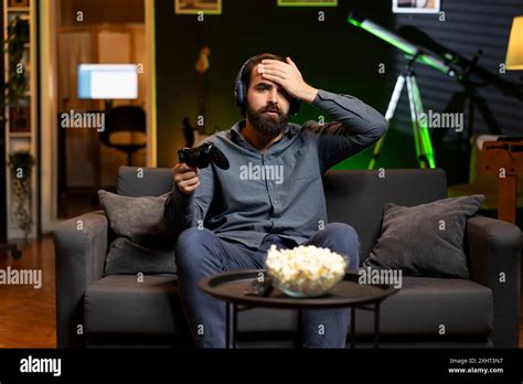 Gamer Wearing Headphones Face Palming Himself In Frustration After Getting Game Over Message