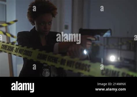 African American Woman Detective With Gun Inspects Dimly Lit Indoor