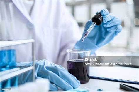 과학자 또는 실험실 코트보유 용 적폐 유리 플라스크의 시약 혼합 화학 액체가 함유 된 유리 제품 실험실 연구 및 현미경 테스트