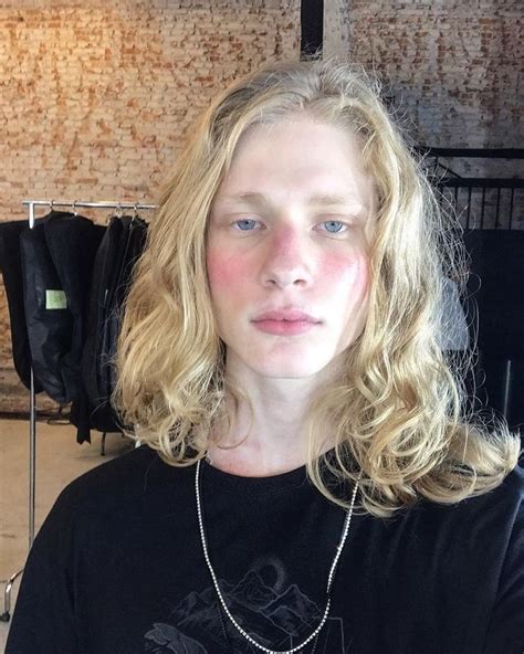A Woman With Blonde Hair And Blue Eyes Wearing A Black T Shirt In A