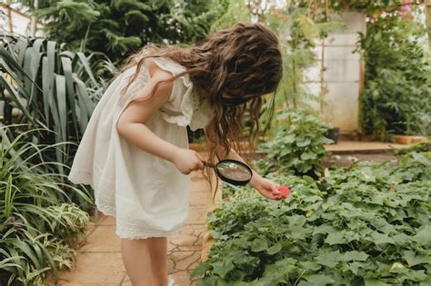 Retrato de una niña linda que mira las plantas a través de una lupa un