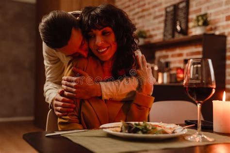 White Couple Hugging While Having Romantic Dinner At Home Stock Photo