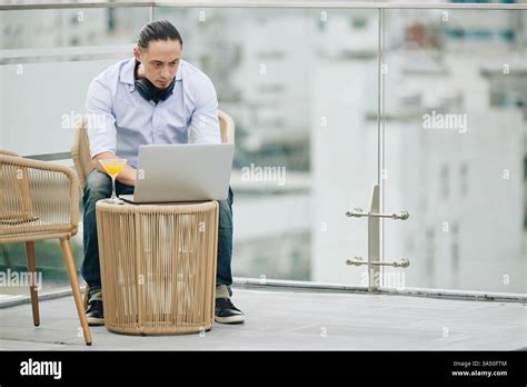 Frowning Young Software Developer Sitting On A Rooftop Programming On A Laptop The Scene