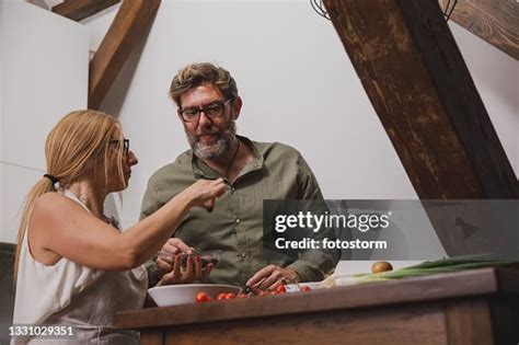 Wife Feeding Her Husband Olives While Preparing Dinner High Res Stock
