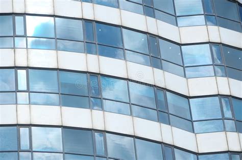 Modern Building Facade With Curved Glass Windows Reflecting Skies Stock