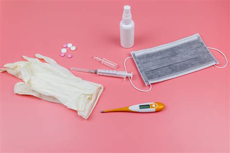 예방 및 치료 코로나 바이러스의 개념 의료 용 마스크 손 소독제 전자 온도계 알약 주사기 앰플 분홍색 배경의 의료 장갑