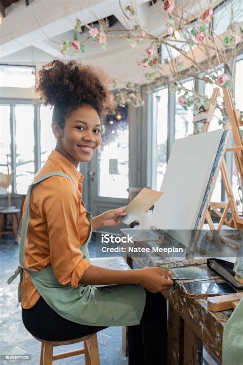아프리카계 미국인 성숙한 여성 예술가가 아트 스튜디오에서 이젤에 그림을 그리는 동안 카메라에 미소를 짓고 있다 게임의 밤 레저 활동에 대한 스톡 사진 및 기타 이미지