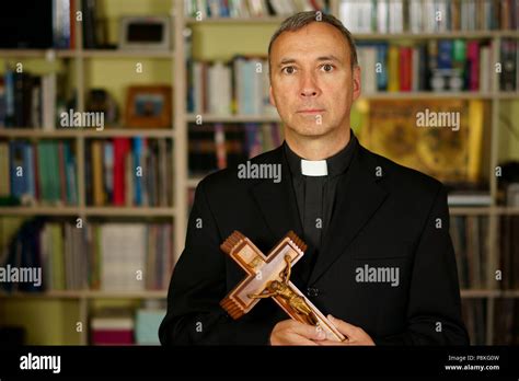 A Good Looking Serious Catholic Priest Is Showing A Crucifix He