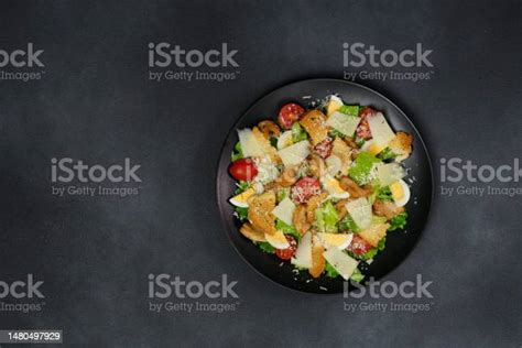 닭고기 양상추 잎 체리 토마토 검은 배경에 검은 접시에 강판 파마산 치즈를 곁들인 시저 샐러드의 상위 뷰 0명에 대한 스톡 사진