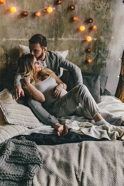 Laughing Young Couple Posing On Bed Del Colaborador De Stocksy