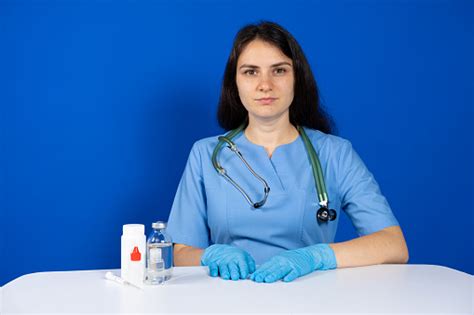 청진기와 장갑을 착용 한 파란색 유니폼을 입은 의사가 의약품이있는 테이블에 앉아 있습니다 수의사에 대한 스톡 사진 및 기타 이미지 수의사 장갑 30 34세 Istock