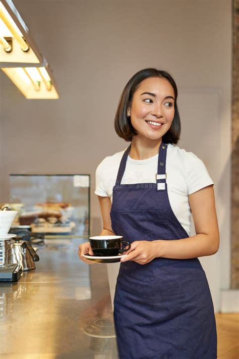 Portrait Of Asian Smiling Barista Girl Serving Coffee Standing Near