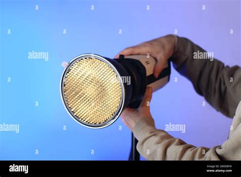 A Flash With The Grid Modifier On Against A Person And A Blue Wall